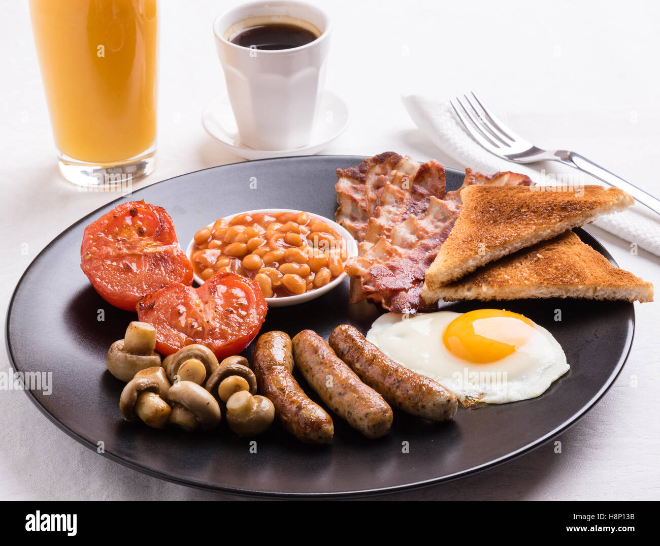 full english breakfast with bacon, sausage, eggs, beans, mushrooms on ...