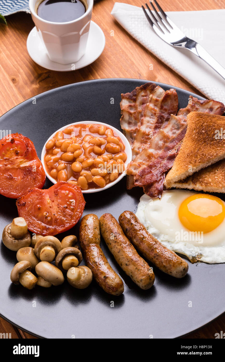 rustic full english breakfast with bacon, sausage, eggs, beans ...
