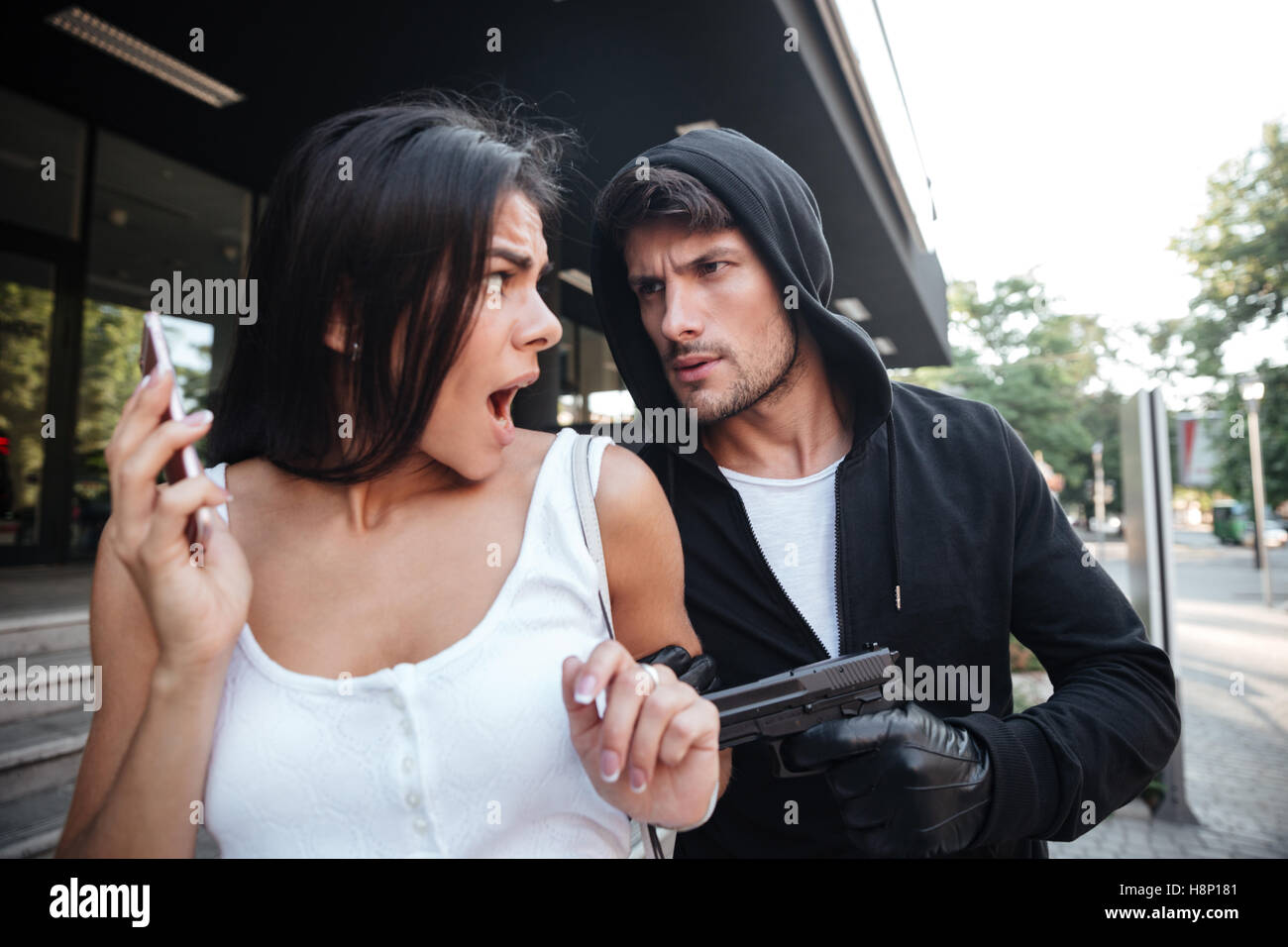 Scared young woman with cell phone screaming and attacked by man robber ...