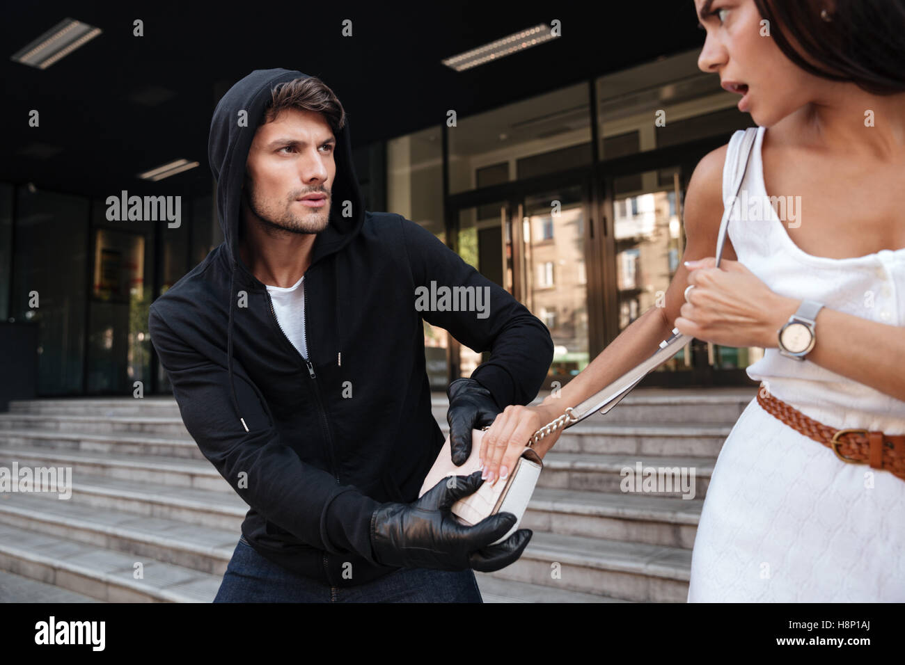 Man thief in black hoodie stealing woman bag on the street Stock Photo ...
