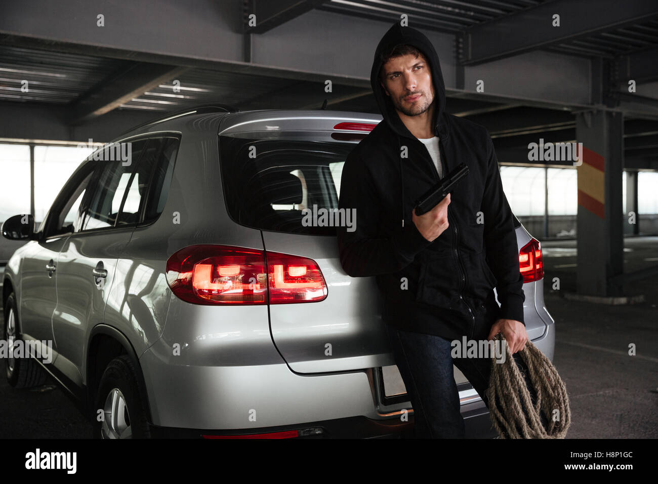Criminal young man holding gun and rope near the car on parking Stock ...