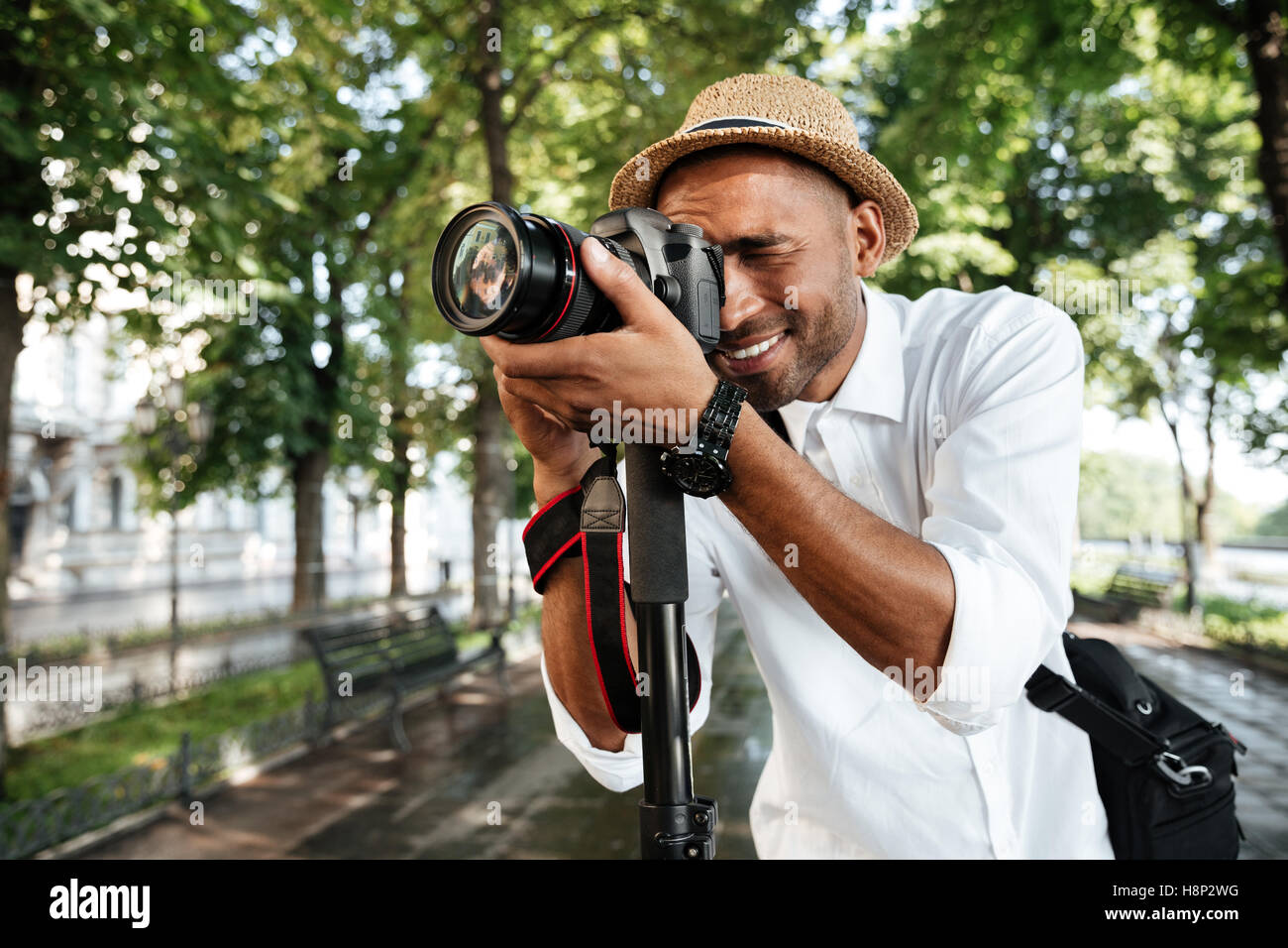 Smiling black man in park with camera Stock Photo - Alamy
