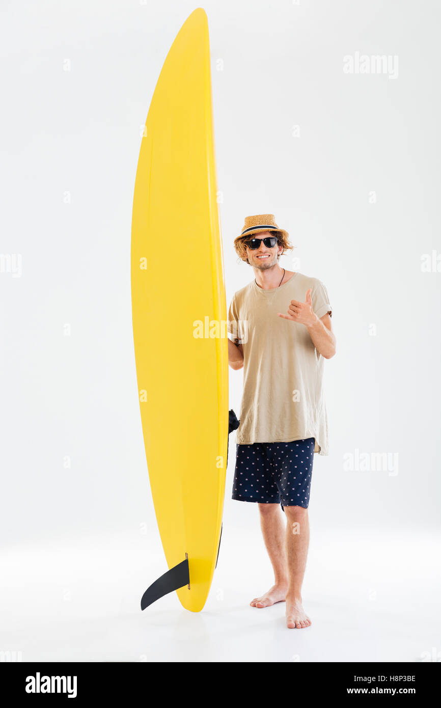 Smiling young curly surfer showing shaka or hang loose sign gesture and ...