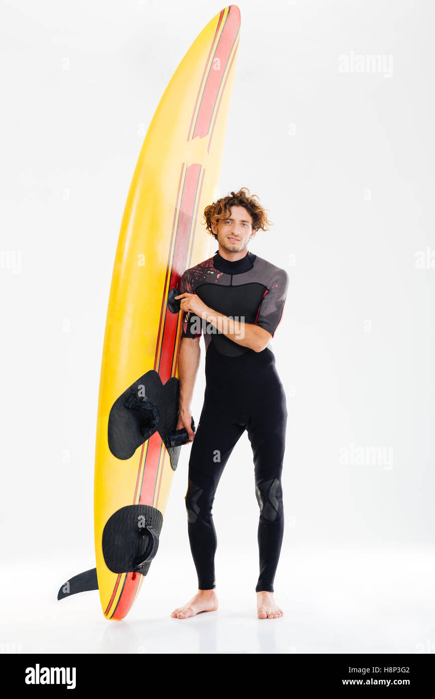 Full length portrait of a young happy surfer holding surf board ...