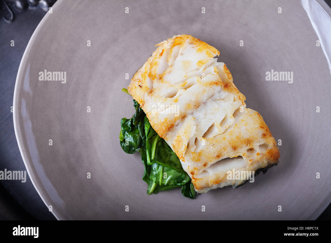 Fried cod fillets and spinach on a plate Stock Photo - Alamy