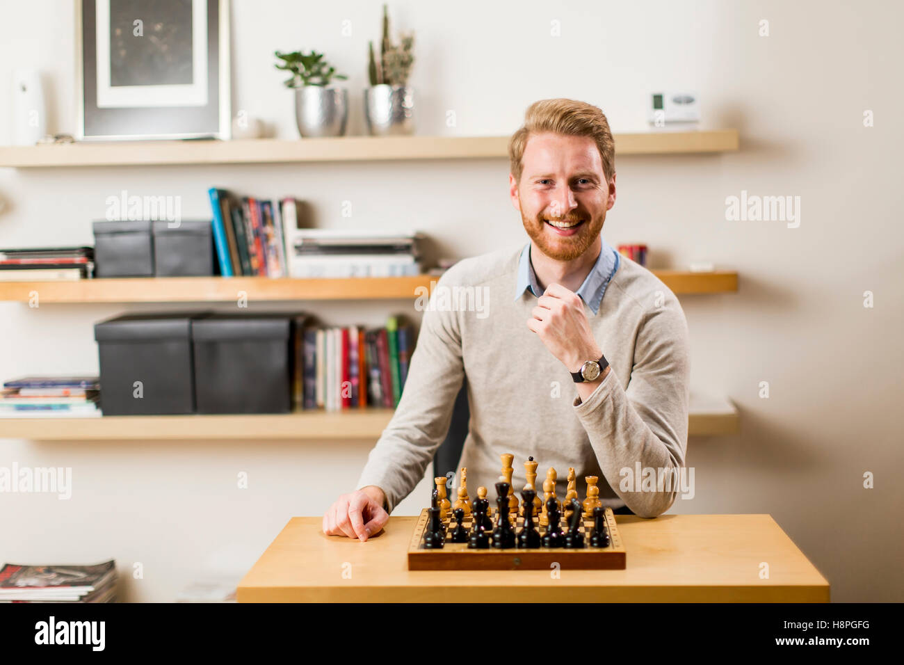 Portrait of a young man is playing a chess and looking at the camera ...