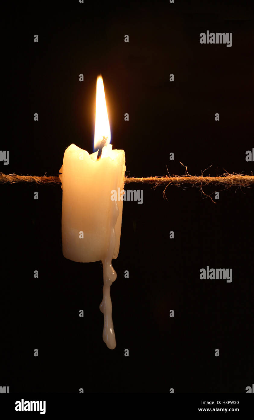 One lighting candle hanging with rope against dark background Stock ...
