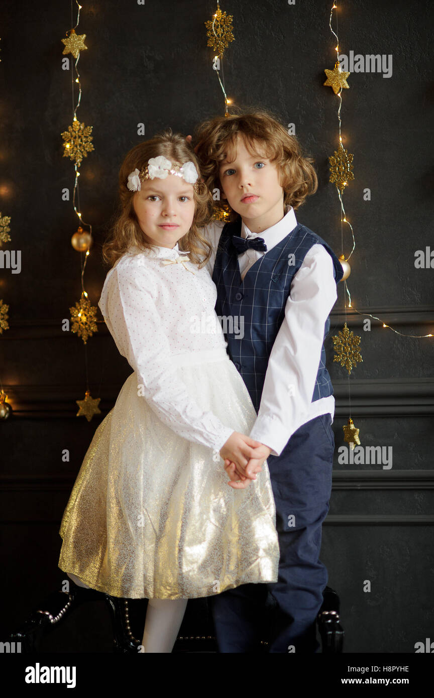 Two charming children stand having joined hands. The girl is dressed in ...