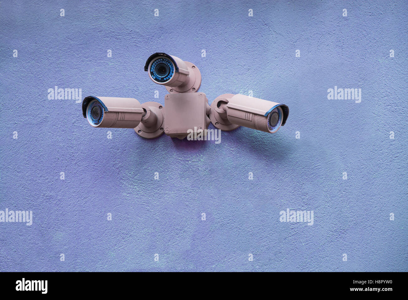 Three security cameras on blue wall Stock Photo - Alamy