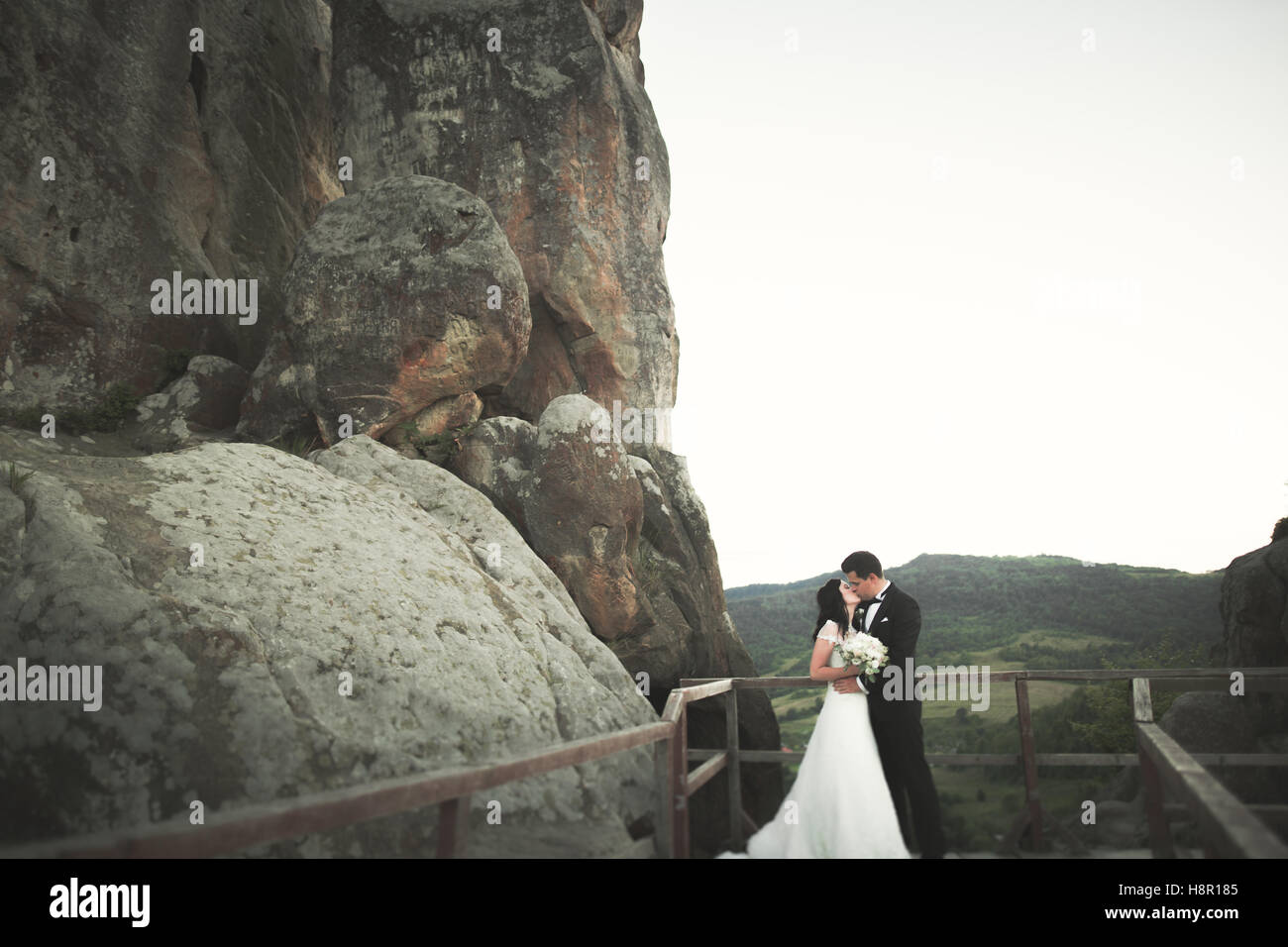 Wedding couple in love kissing and hugging near rocks on beautiful ...