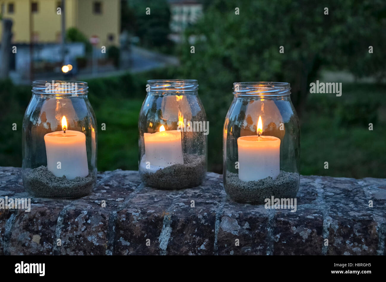 View of glass jars with lit candles inside Stock Photo - Alamy