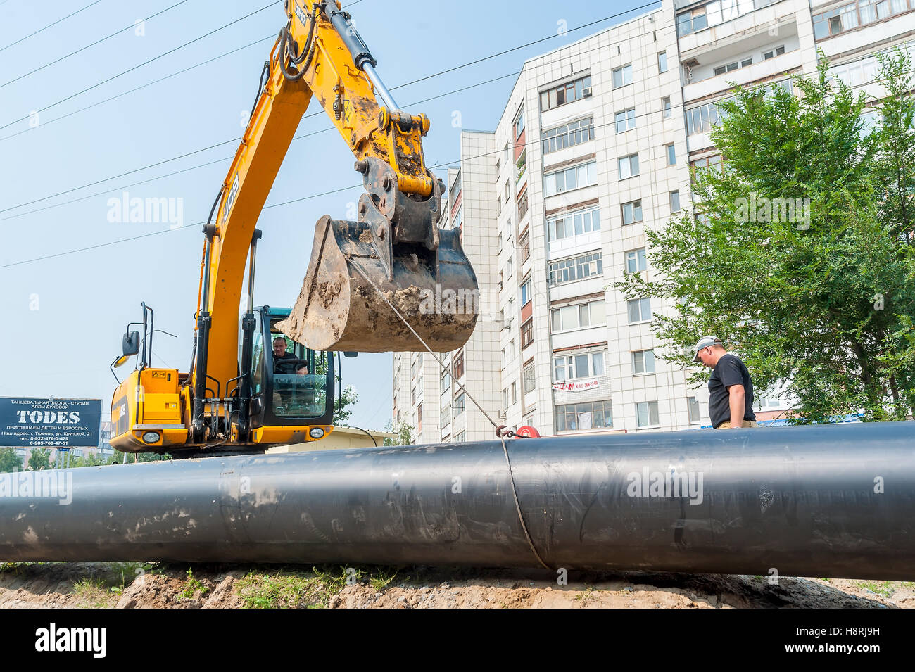 Using of excavator as crane for raising of tube Stock Photo - Alamy