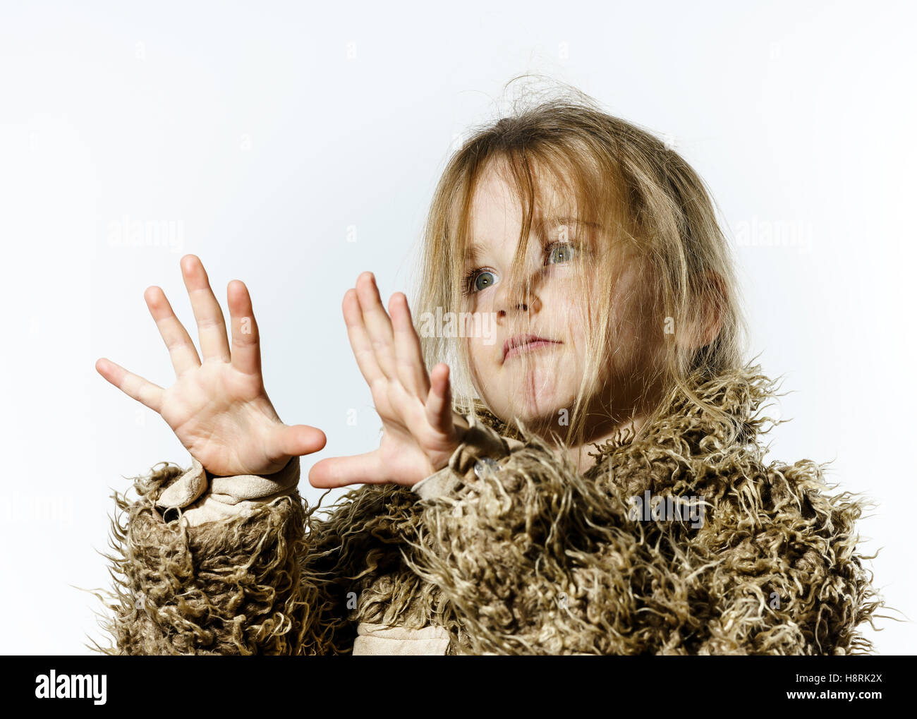 Disheveled preschooler girl with long hair dressed in fur coat ...