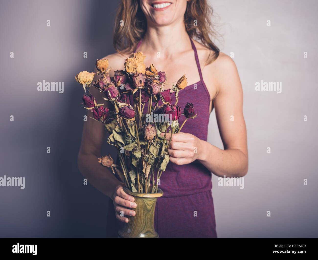 A young woman is standing with a bouquet of dead flowers Stock Photo ...