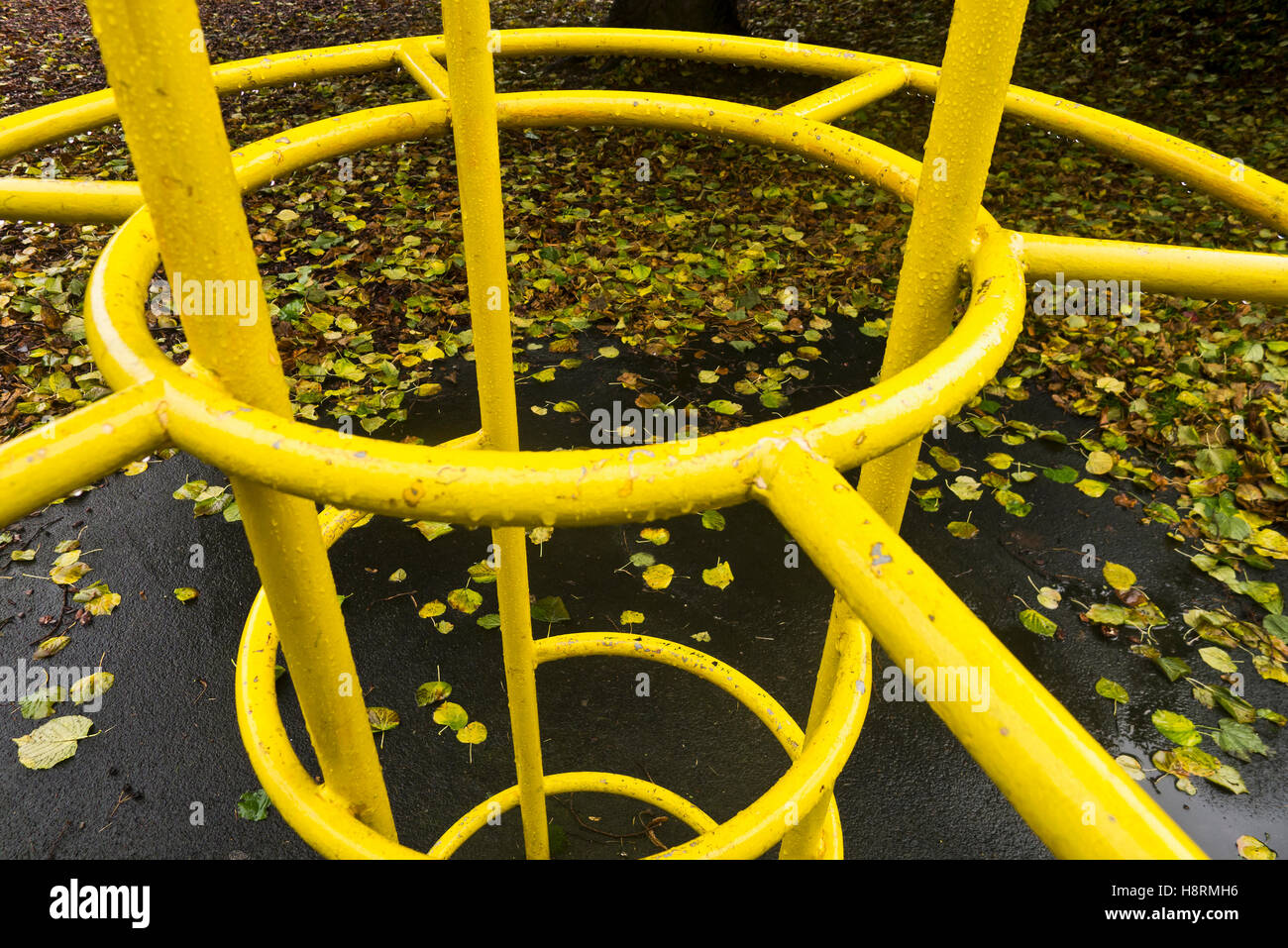 Yellow climbing frame in the rain with Autumn leaves Stock Photo - Alamy