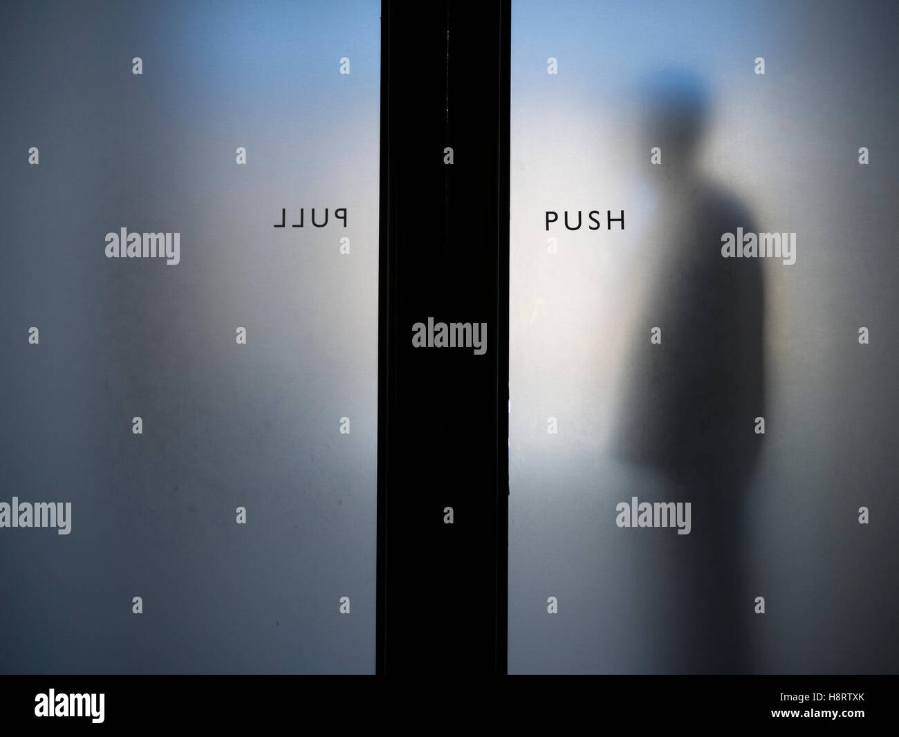 Silhouette of a man behind glass panel door with words push and pull ...