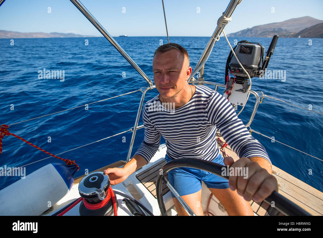 Young man at the helm of his yacht Stock Photo - Alamy