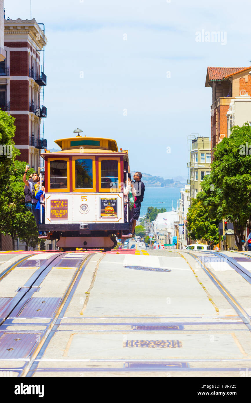 Oncoming cable car is full of outside hanging and platform standing ...