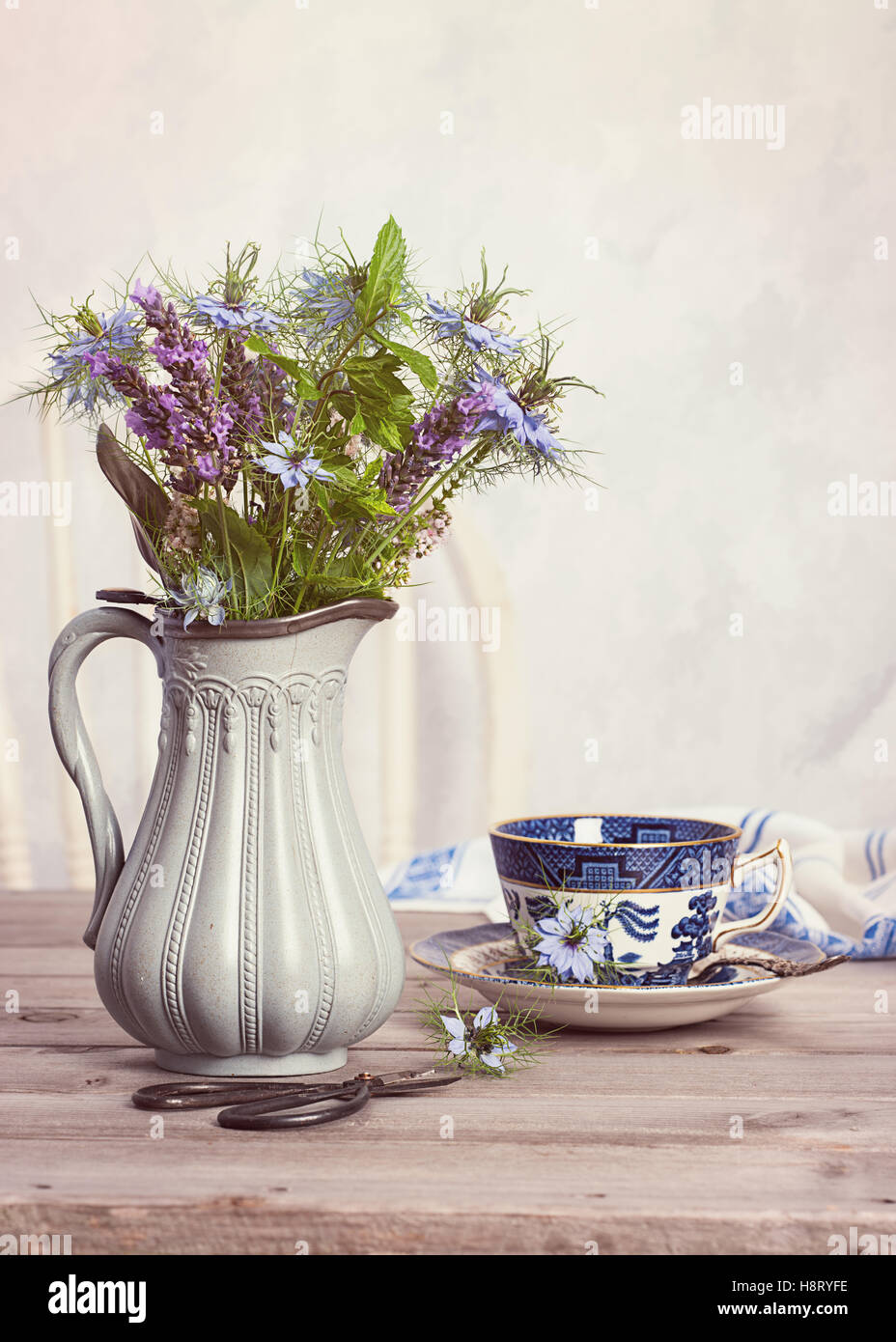 Flowers in antique jug with cup of tea Stock Photo - Alamy