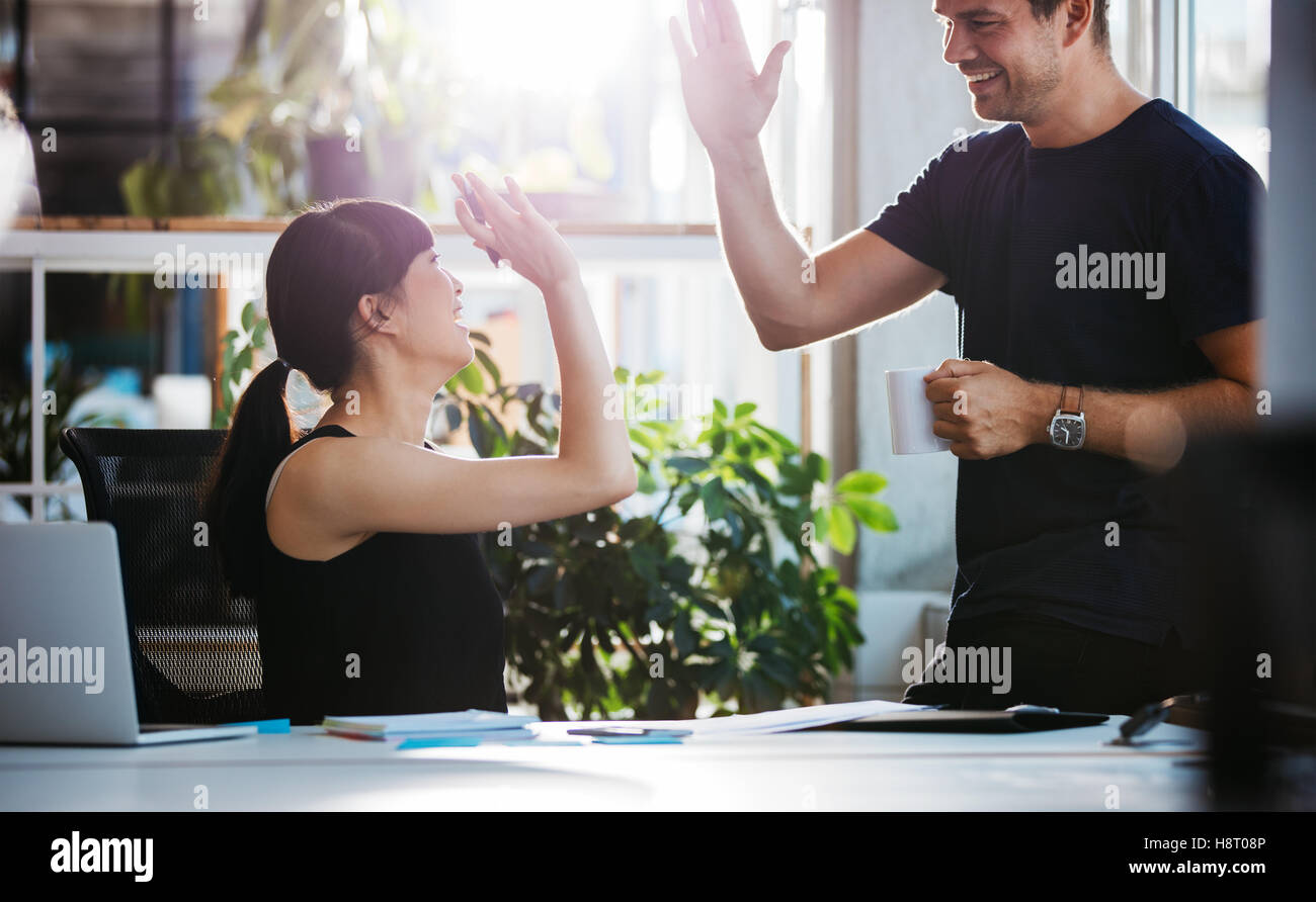 Shot of happy and successful business colleagues giving high five in ...