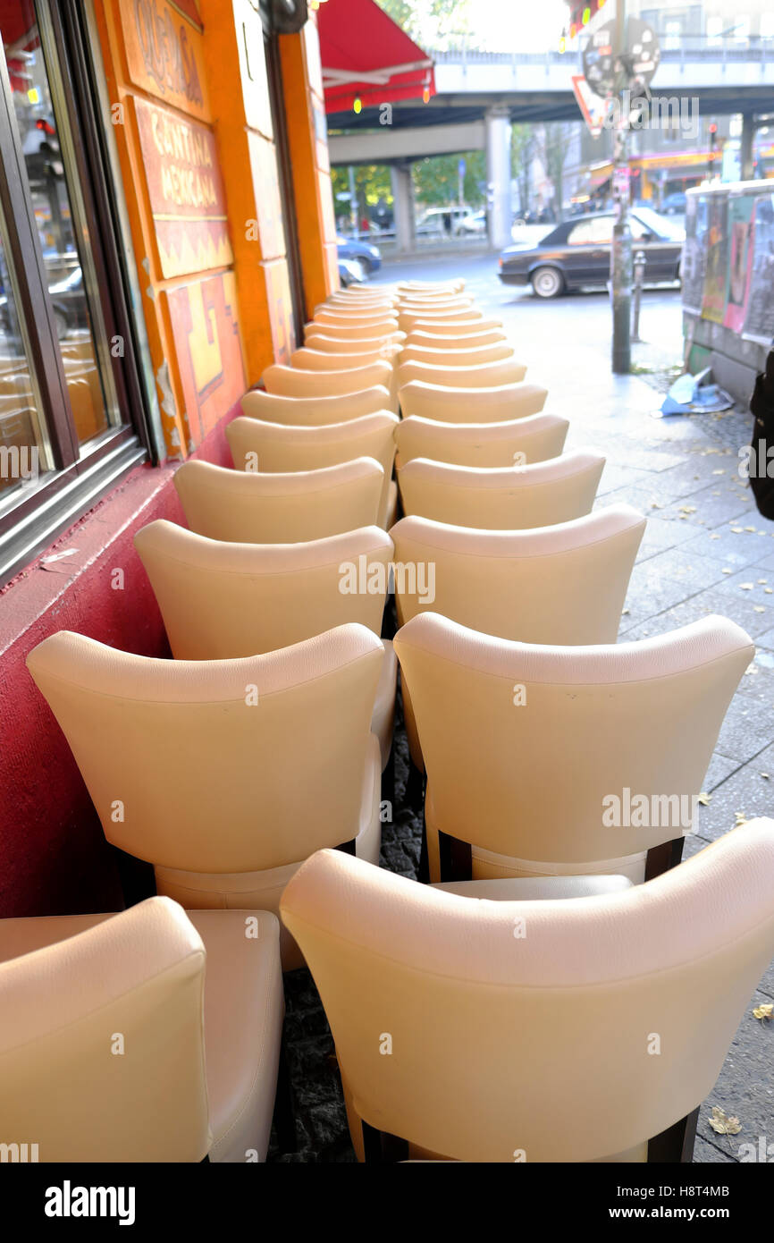 Dining chairs lined up on the pavement outside a restaurant in a street ...