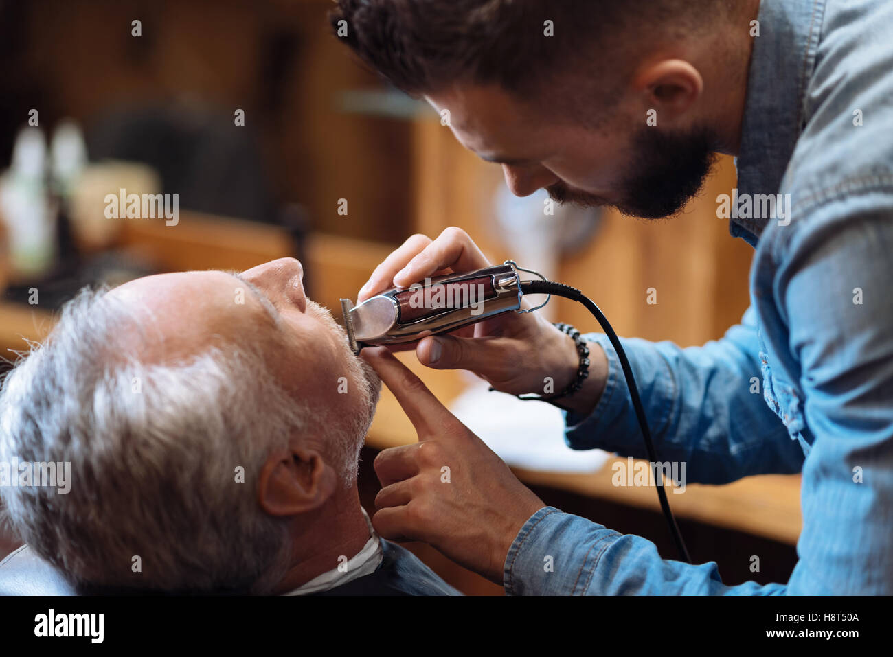 Side view of young barber trimming beard Stock Photo - Alamy