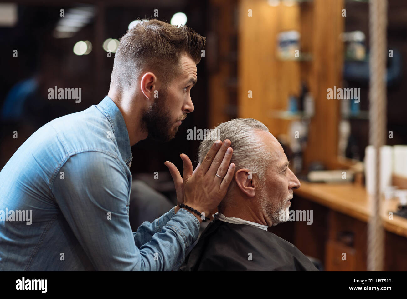 Handsome barber styling hair of senior man Stock Photo - Alamy