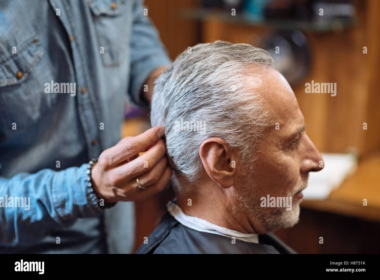Barber styling hair of senior client Stock Photo - Alamy