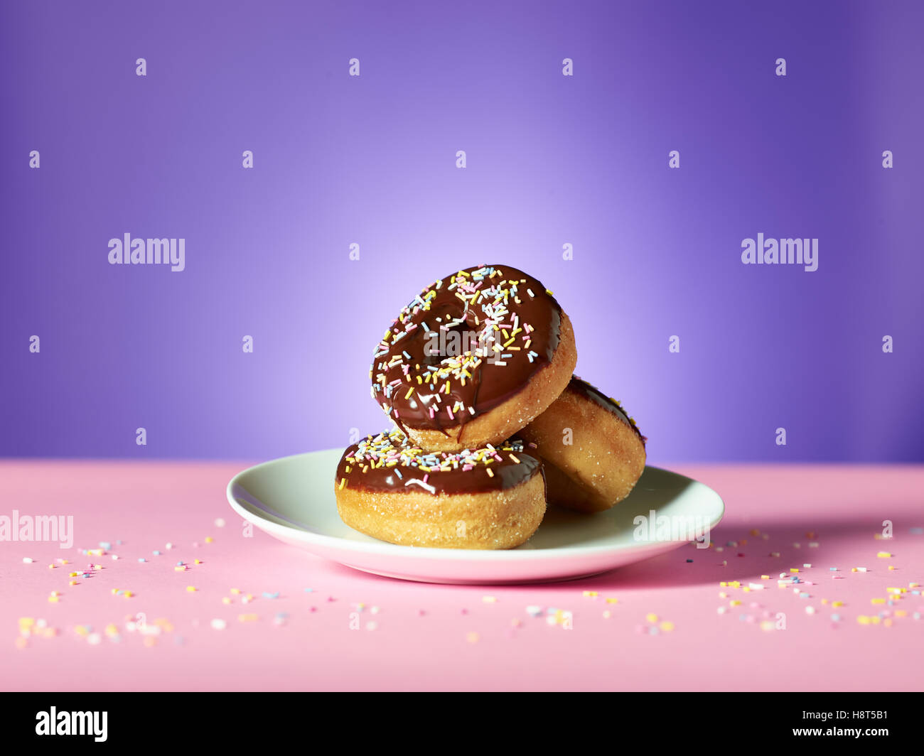Stack of chocolate covered donuts with sprinkles Stock Photo - Alamy