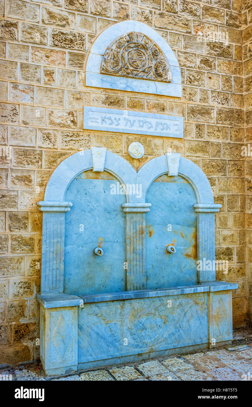 The old marble fountain with the hebrew inscriptions and patterned ...