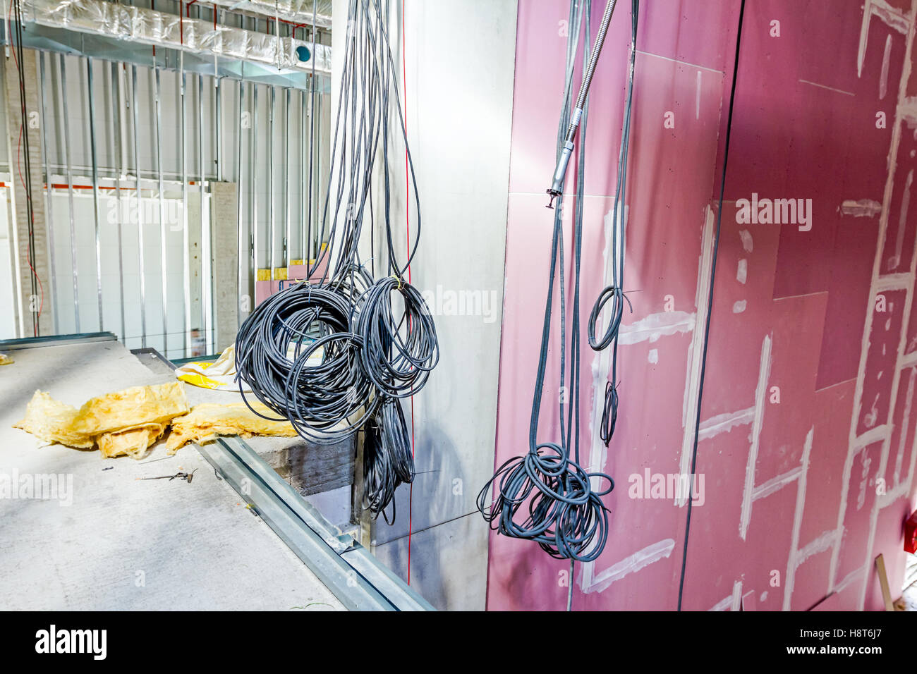 Bundle of various cables are hanging from above in indoor building site ...