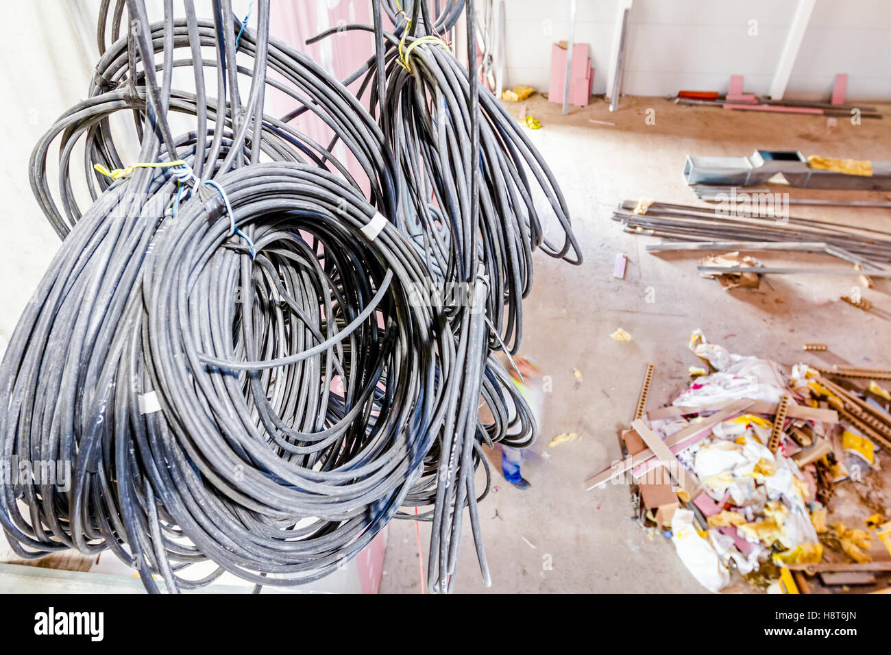 Bundle of various cables are hanging from above in indoor building site ...