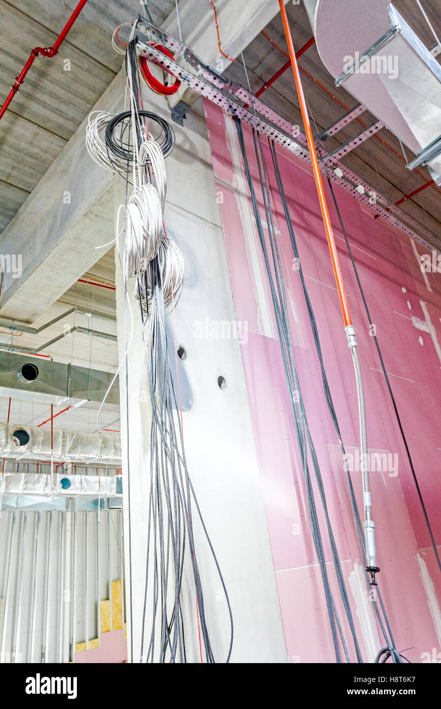 Bundle of various cables are hanging from above in indoor building site ...