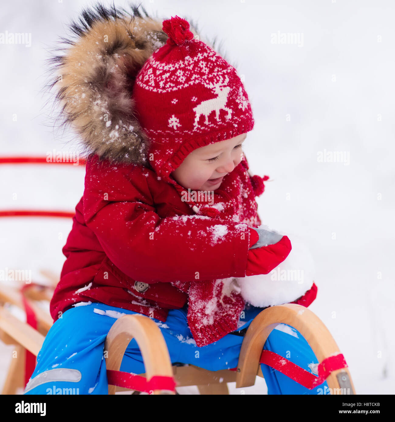 Little girl enjoying a sleigh ride. Child sledding. Toddler kid riding a sledge. Children play ...