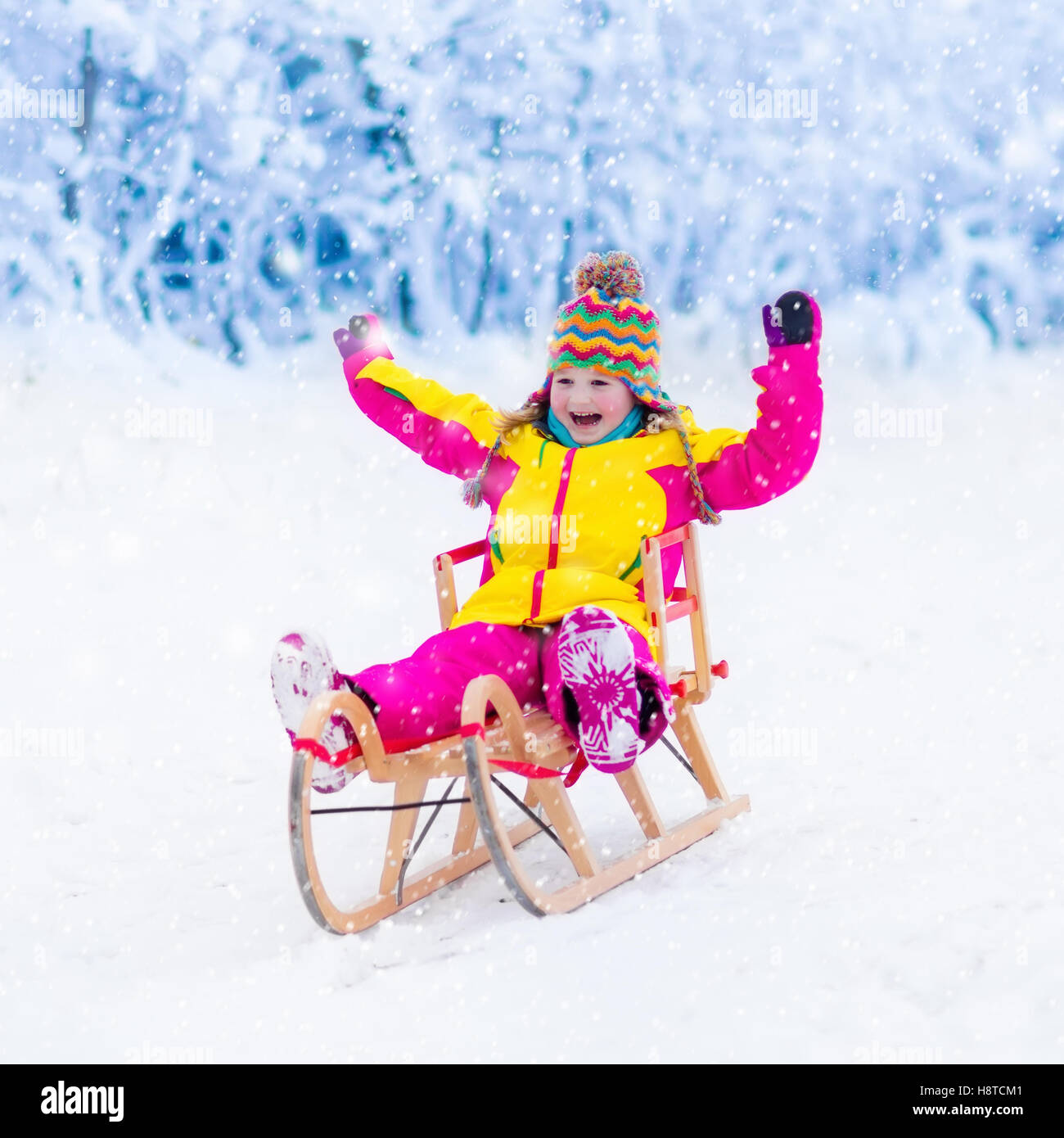Little girl enjoying a sleigh ride. Child sledding. Toddler kid riding a sledge. Children play ...