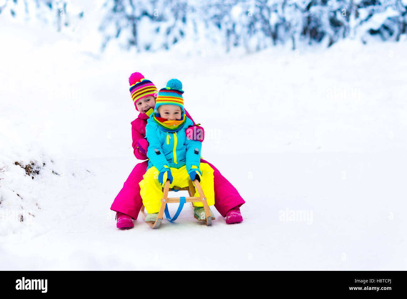 Little girl and boy enjoying sleigh ride. Child sledding. Toddler kid ...