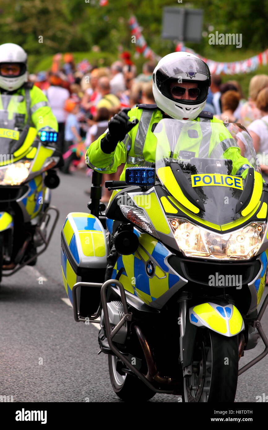 British police officer riding a motorbike past crowds of people Stock ...