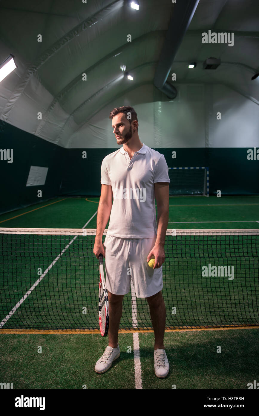 Pleasant confident tennis player standing in the indoor court Stock ...