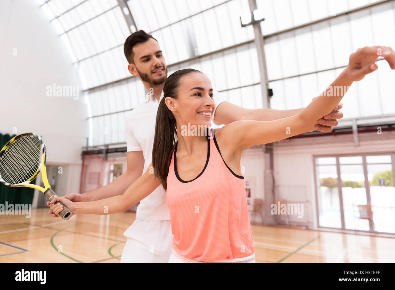 Professional tennis instructor showing woman how to serve the ball ...