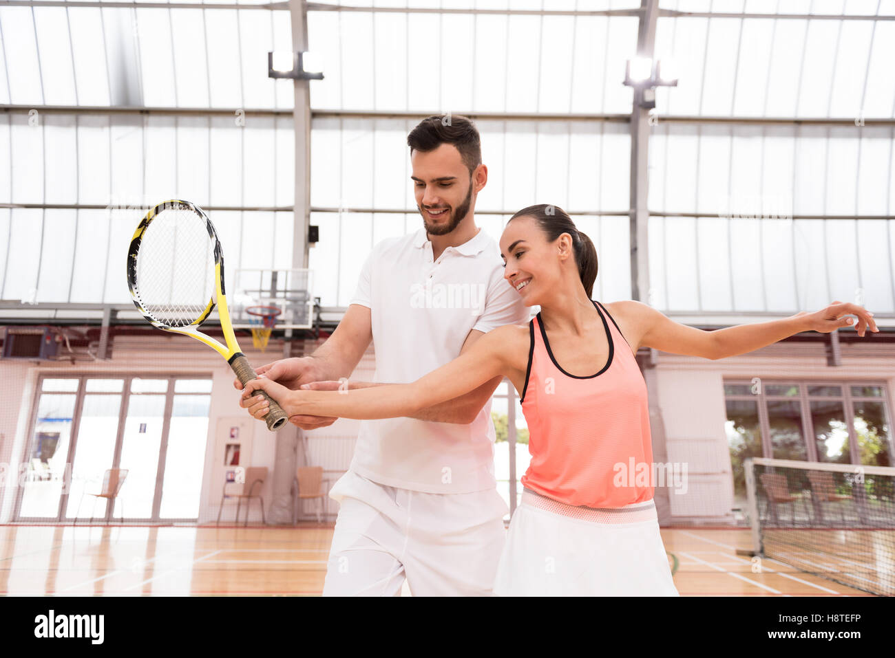 Cheerful tennis instructor showing how to hold racket Stock Photo - Alamy