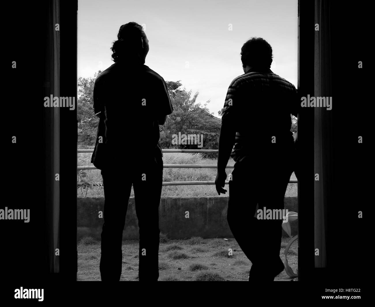 Silhouette of two men who standing at the front door while conversing ...