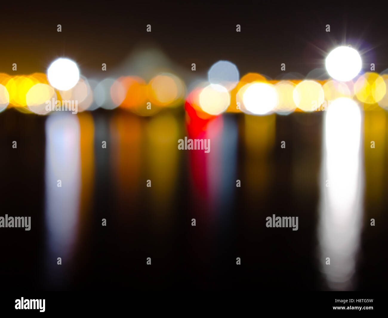Blur/defocus shot of colorful lights on a pier and its reflections on ...