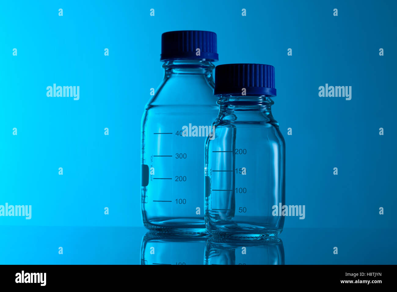 Labotatory test glass container on a blue background Stock Photo - Alamy