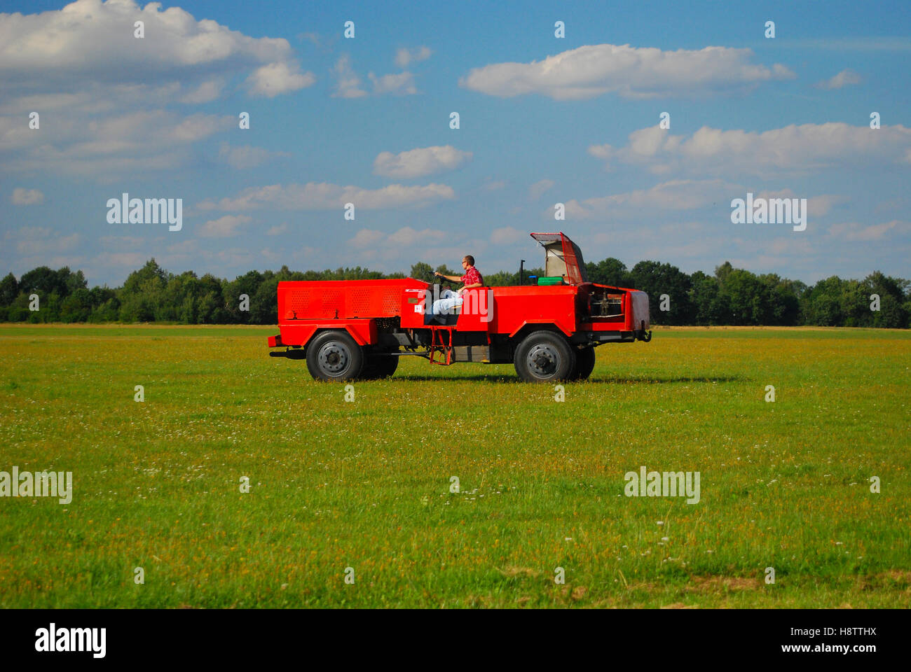 some old firetruck standing on grass with driver inside Stock Photo - Alamy