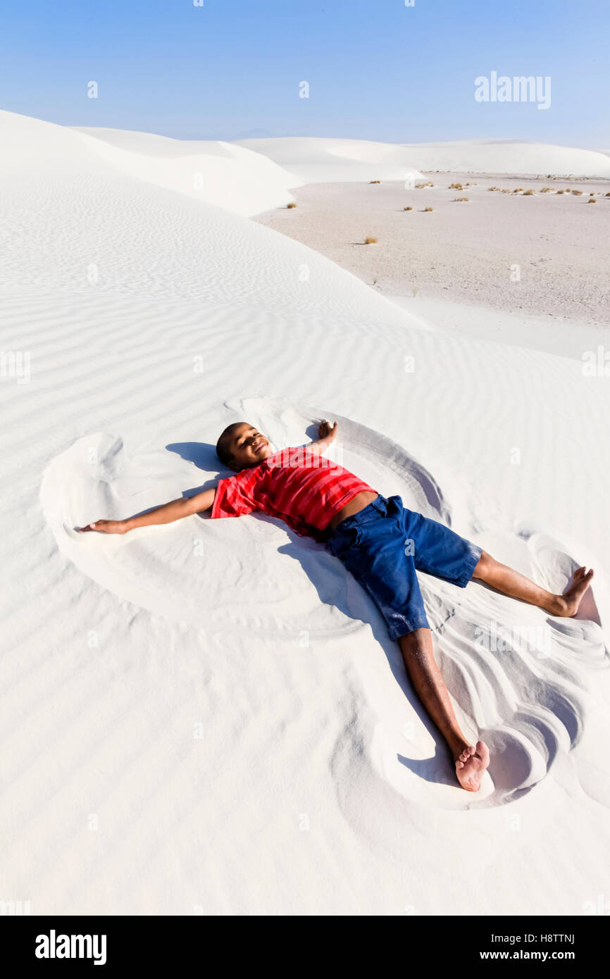 Boy makes a "snow angel" in the sand at White Sands, New Mexico, USA ...