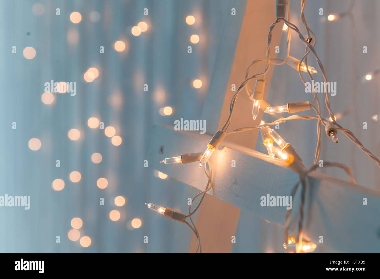 Christmas lights burning on a white wooden background. New Year back ...