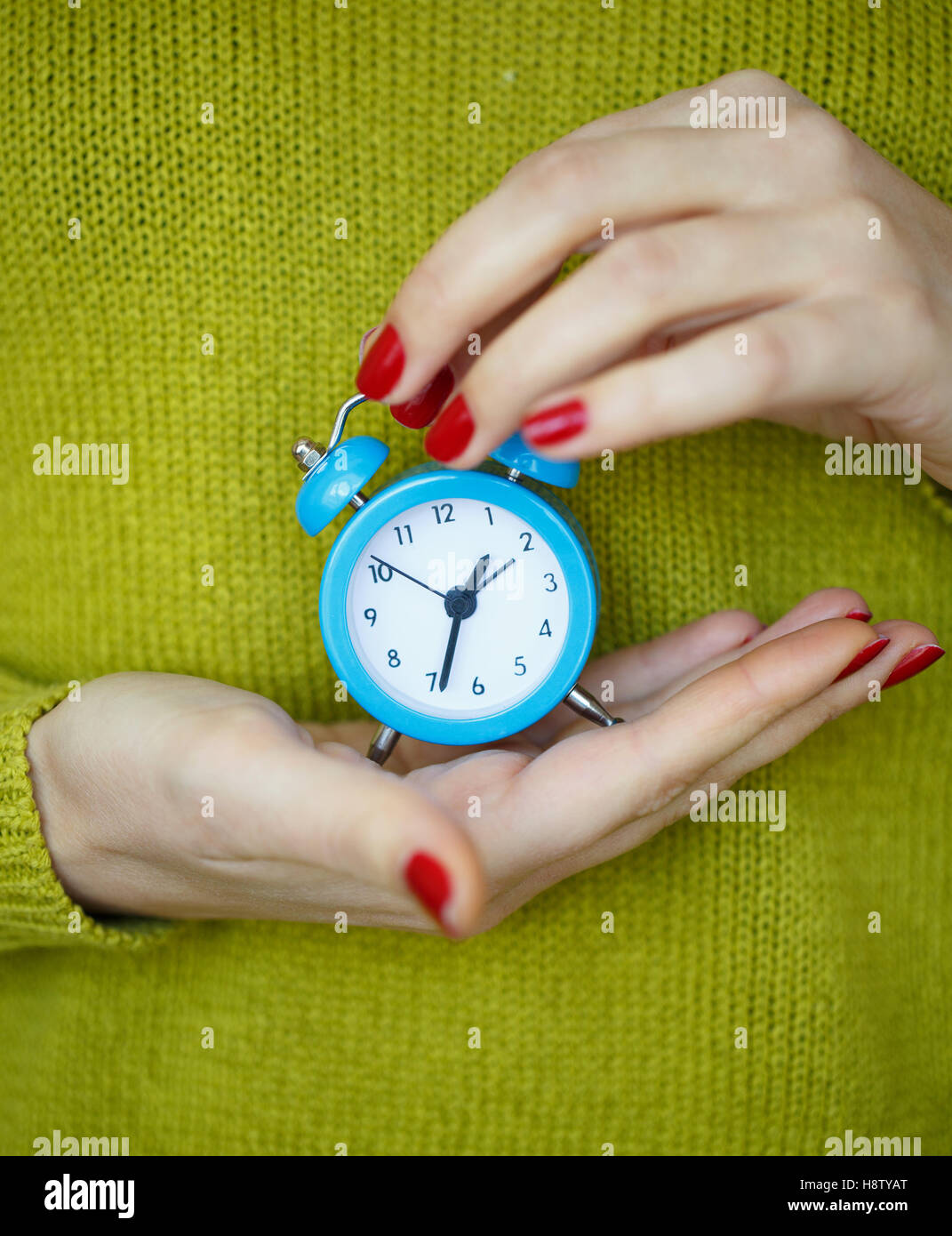 Little blue alarm clock in the hands of pensive young woman, concept of ...
