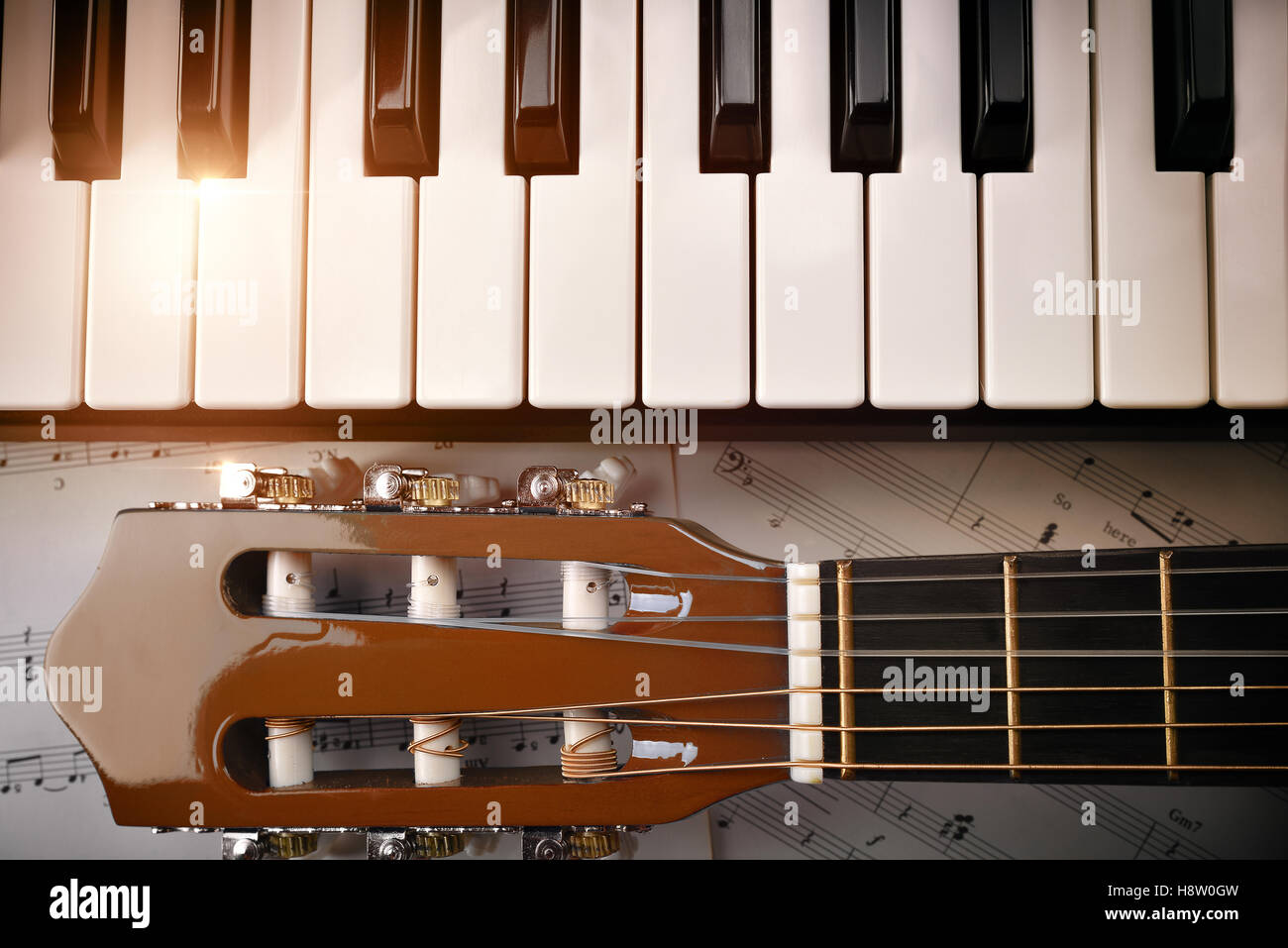Piano and tuning peg guitar with shine and sheet music background ...