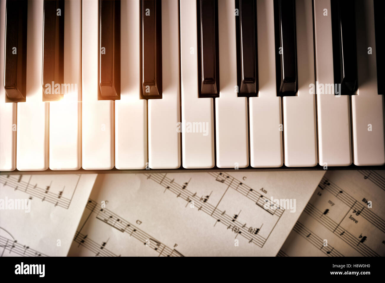 Piano keyboard with golden shine and sheet music. Horizontal ...