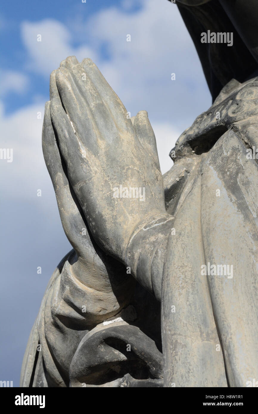 Praying hands on gravestone against cloudy sky Stock Photo - Alamy